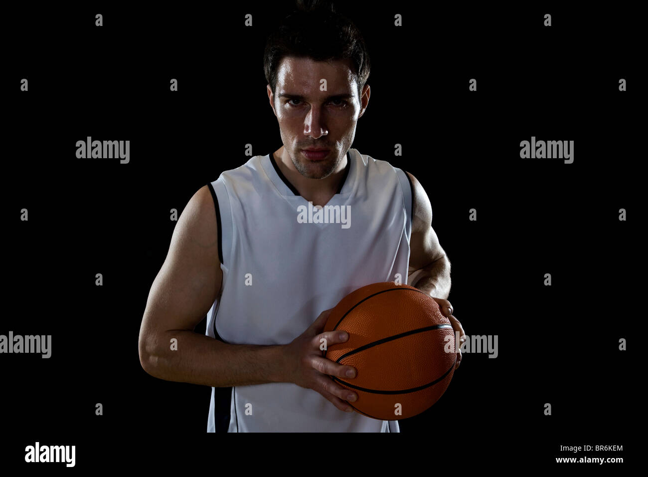 A basketball player preparing to pass a ball, portrait, studio shot ...
