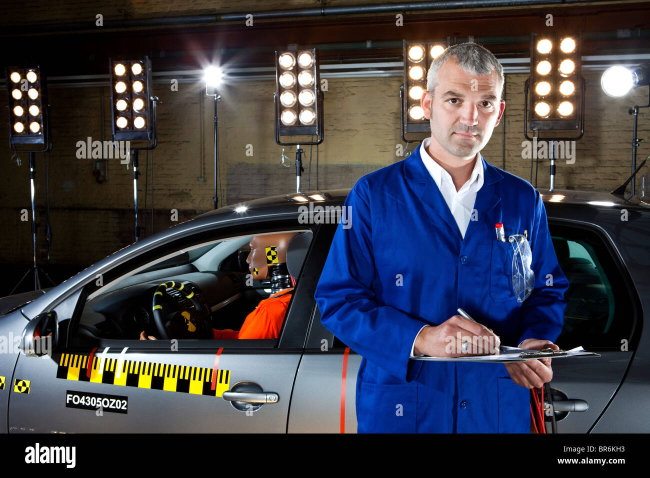 A researcher next to a car with a crash test dummy in a crash test ...