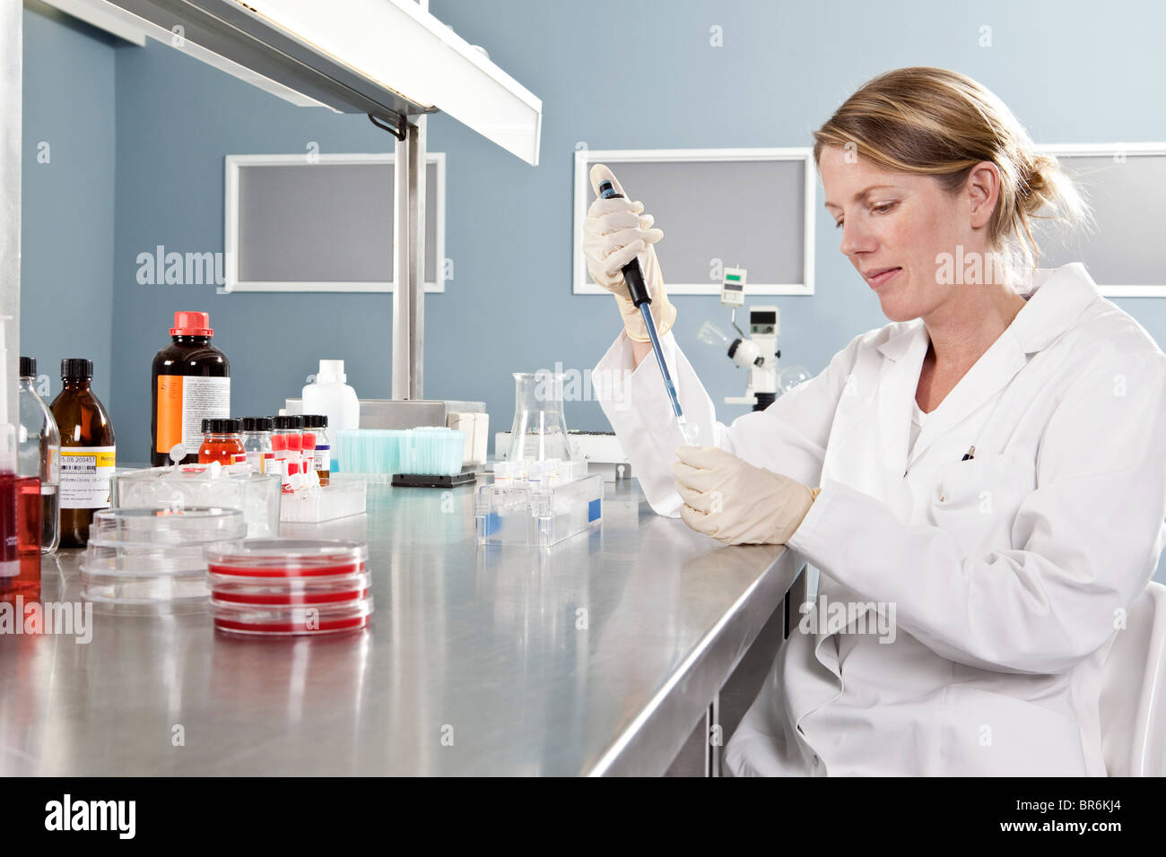 A lab technician using a pipette to put a sample into a vial Stock ...