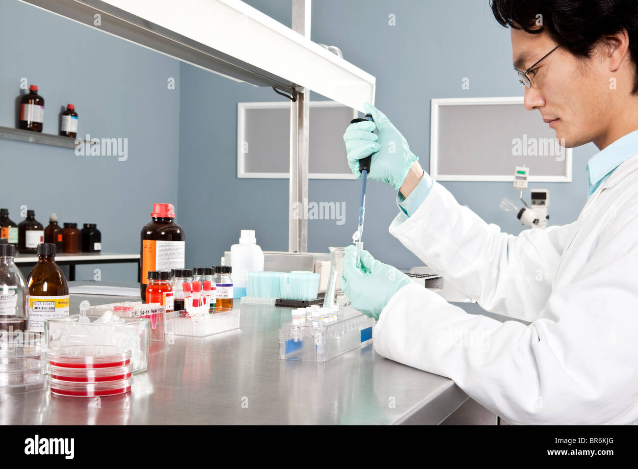 A lab technician using a pipette to put a sample into a vial Stock ...