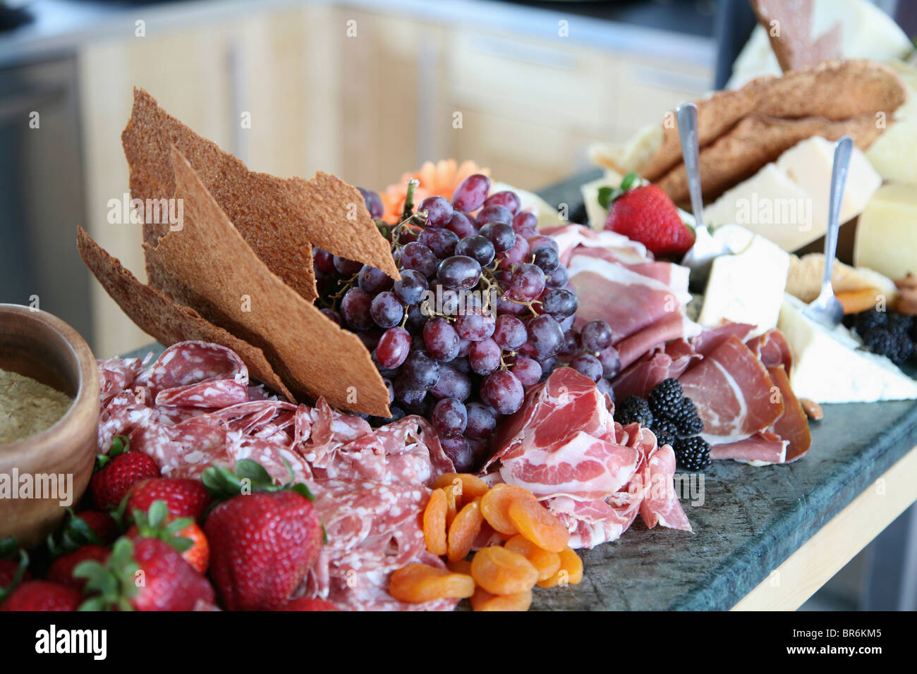 Selection of cold meats, cheeses and fruits on a kitchen counter Stock ...