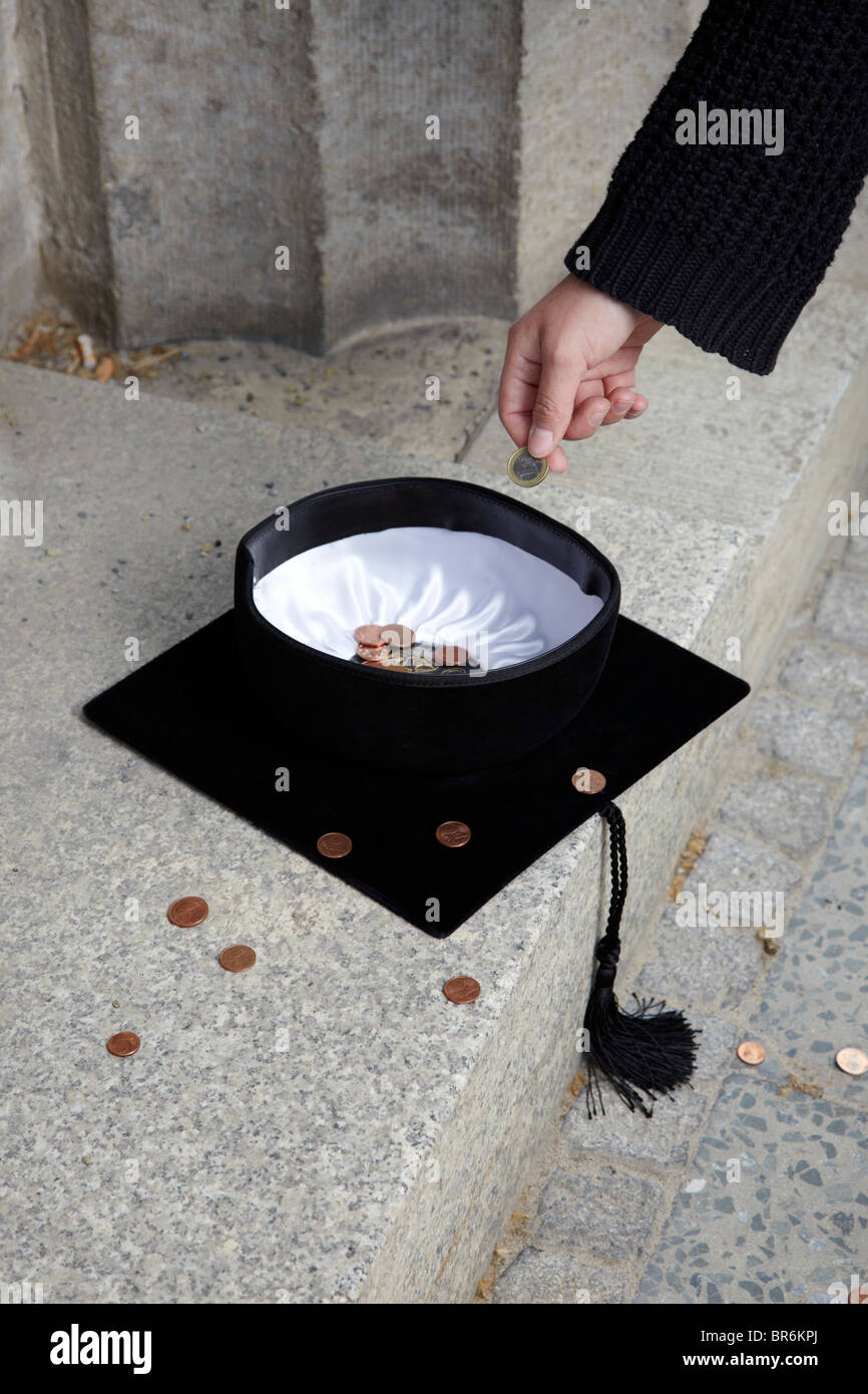 Man dropping coin into mortarboard Stock Photo - Alamy