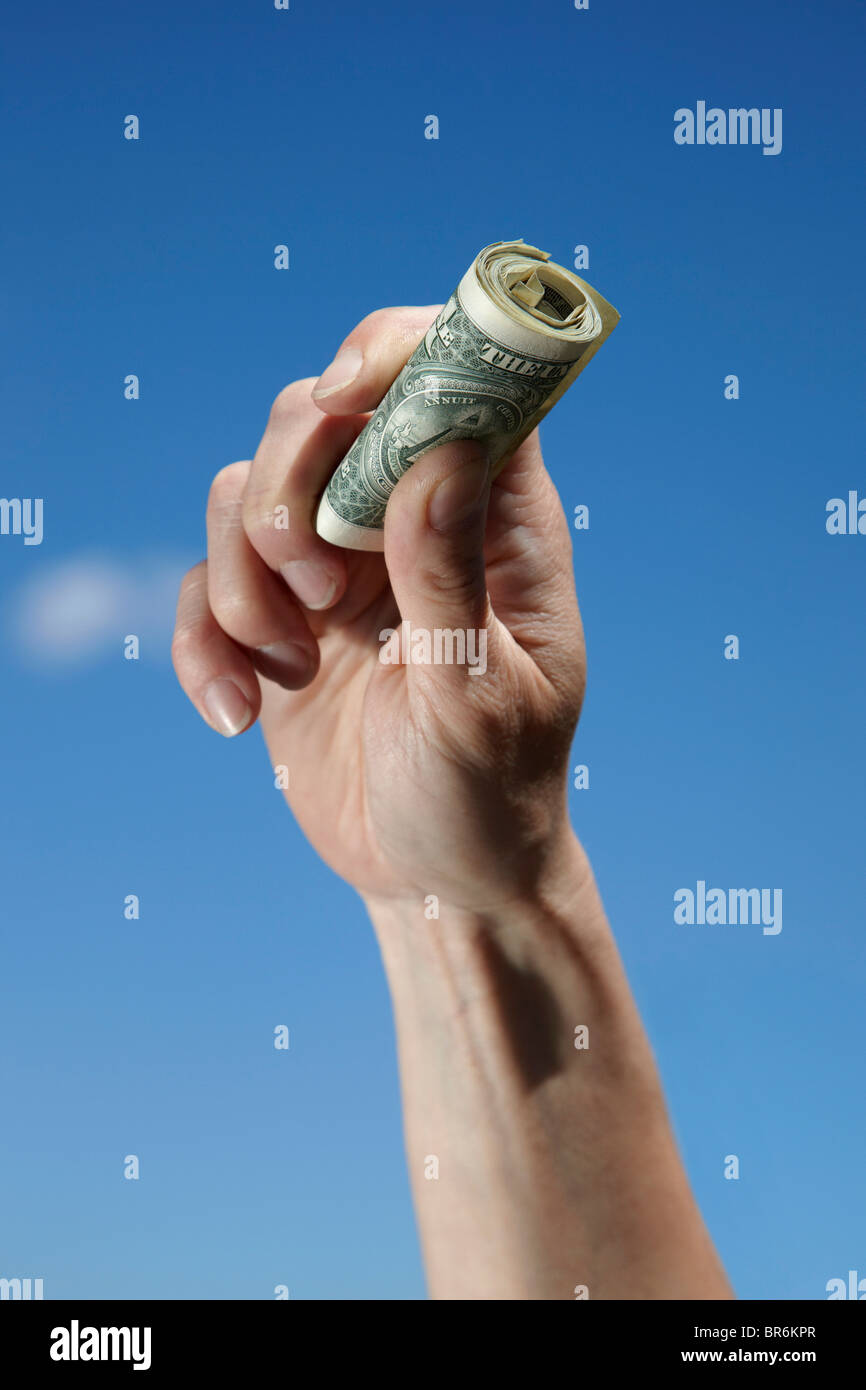 Hand holding roll of dollars Stock Photo - Alamy