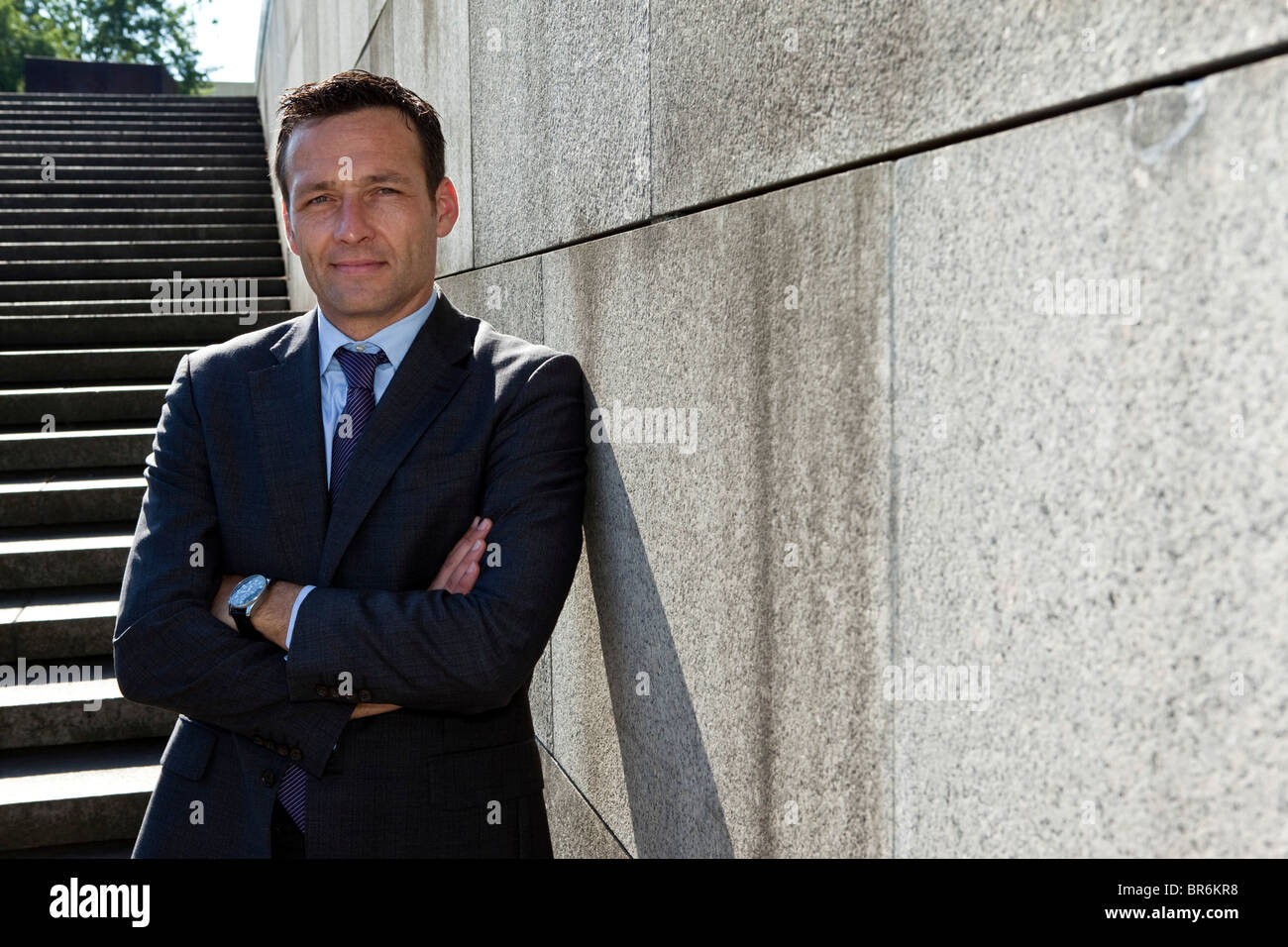 Portrait of a businessman leaning against a wall, outdoors Stock Photo ...