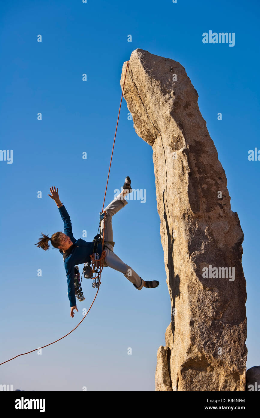 Climber in trouble dangling from her rope as she scales a rock pinnacle ...