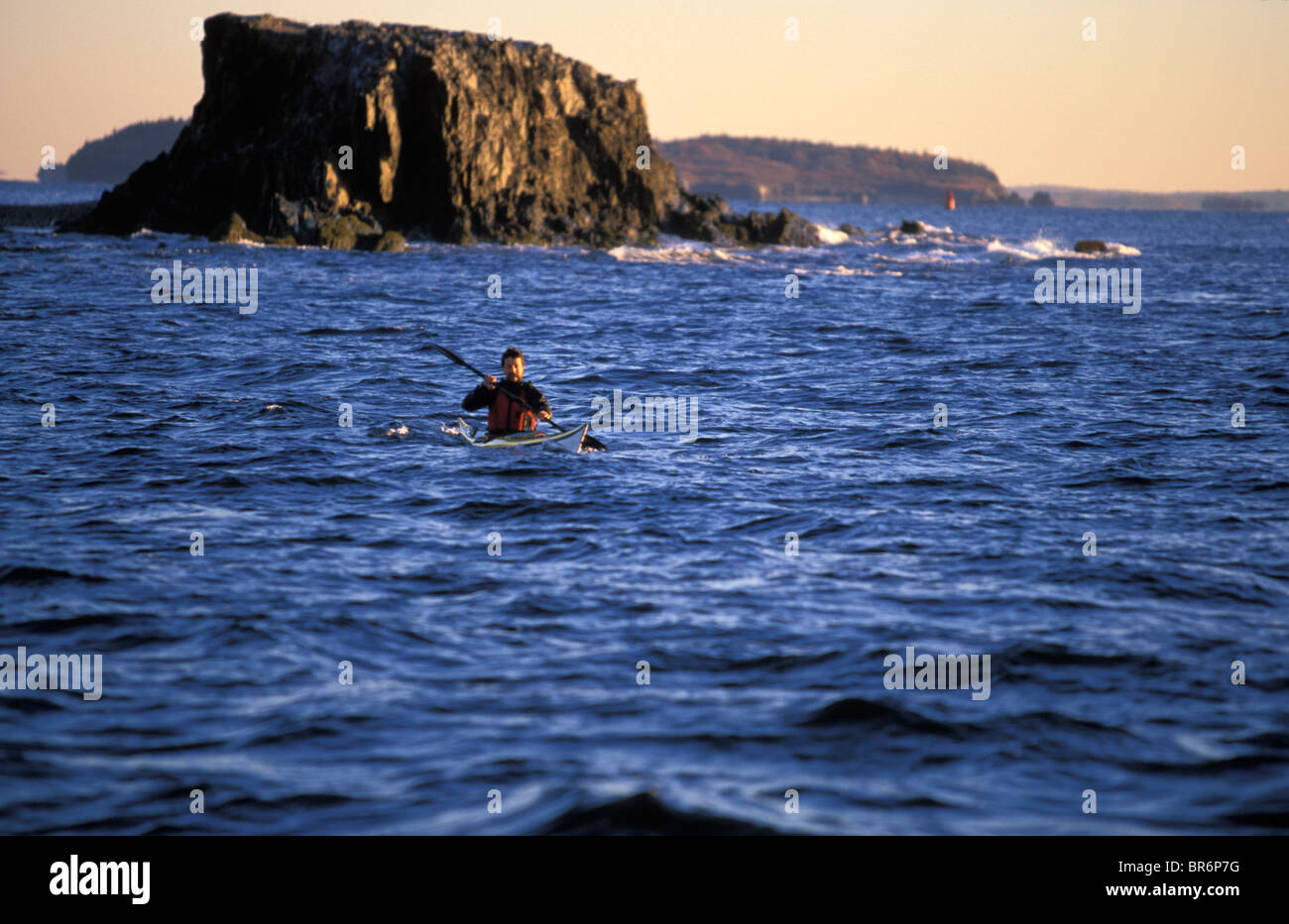 A male kayaker sea kayaking in a bay near the ocean at sunset Stock ...