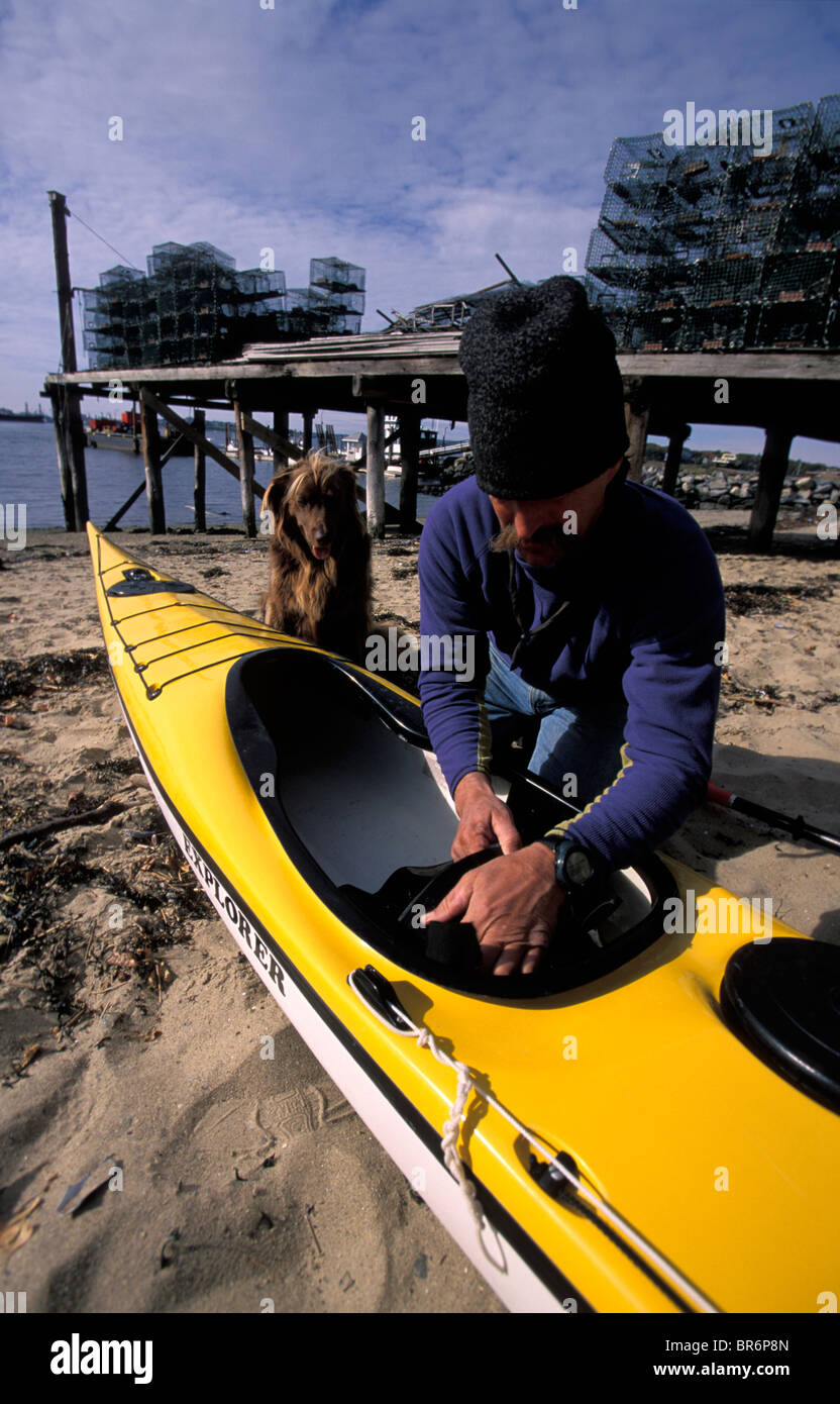A man on the beach prepares his sea kayak for a day of sea kayaking on ...