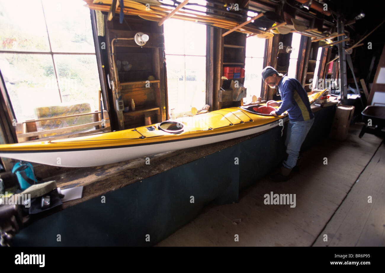 A man in a boathouse prepares his sea kayak for a day of sea kayaking ...