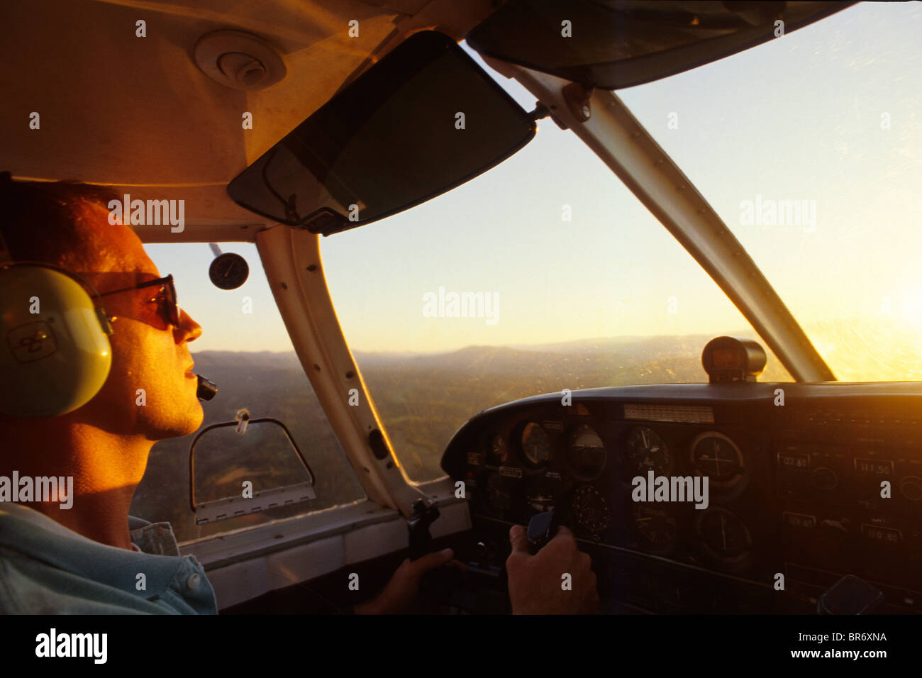 Male pilot flies his aircraft into the setting sun Stock Photo - Alamy