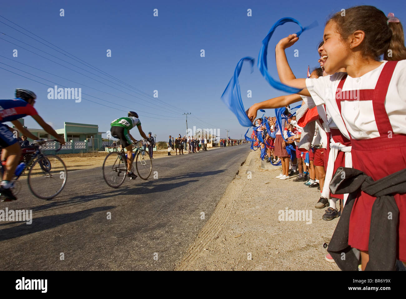 Children wave handkerchiefs at cyclers as they go past in the street in ...