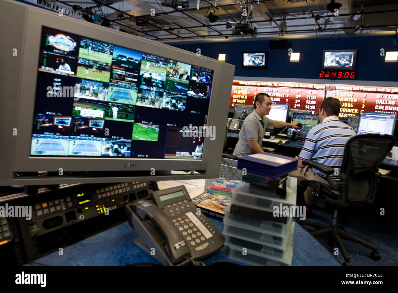 Two men work in a room filled with TV screens and computer monitors ...