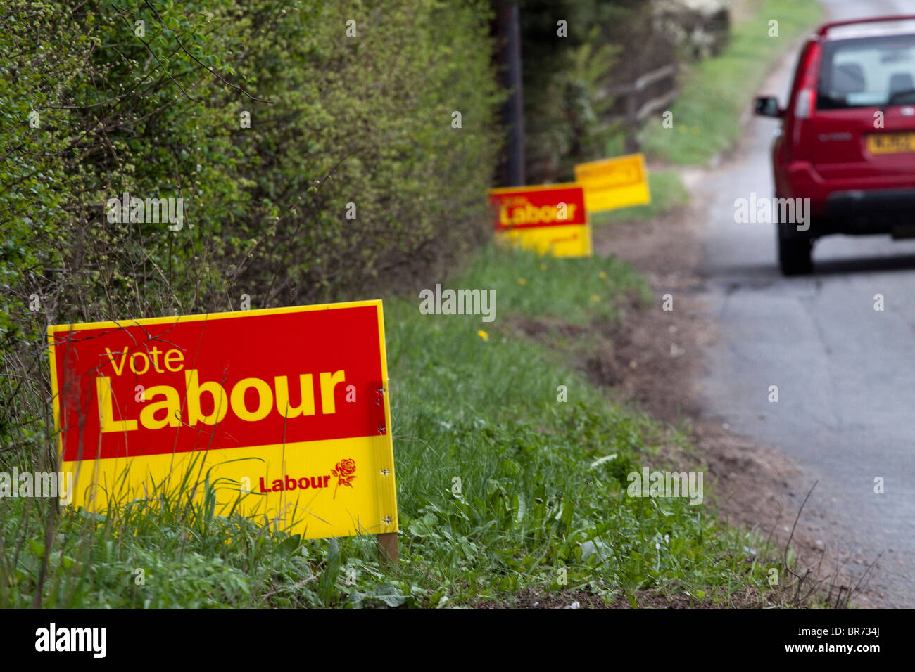 Red and yellow "Vote Labour" placards on a grass verge in rural Suffolk ...