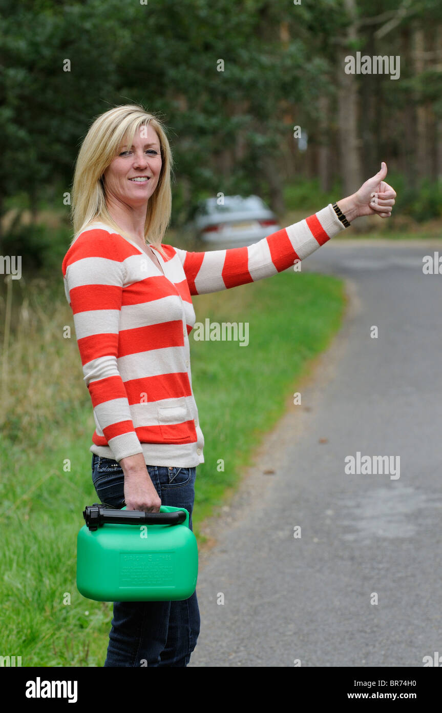Female motorist thumbing a lift on a country lane holding a 5 litre ...