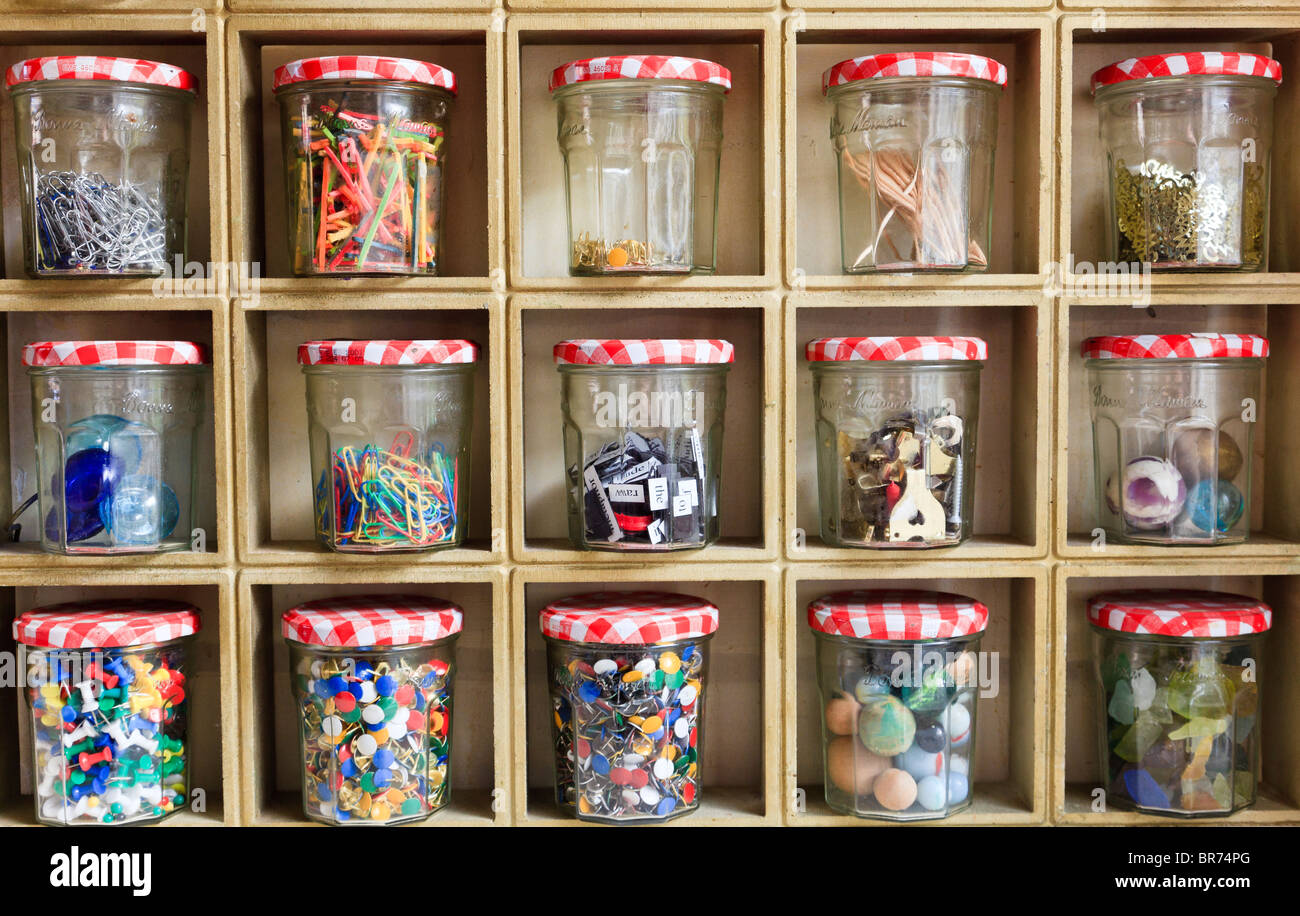 collection of coloured objects stored in old Jam Jars on squared shelf ...