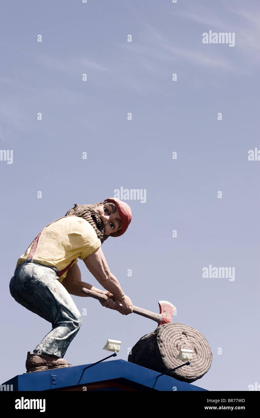 A statue of an old-fashioned logger chops wood atop a building in ...