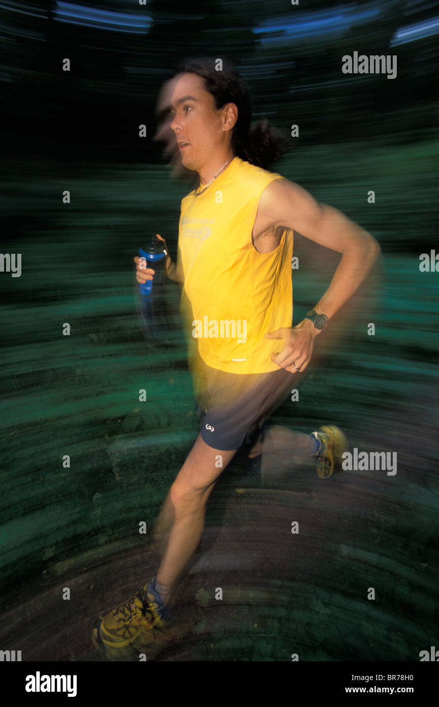 Man in a yellow shirt running in the forest in the Cascade mountains ...