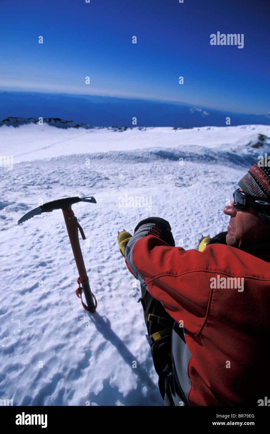 A climber and his axe take in the view from the summit of Mount Rainier ...