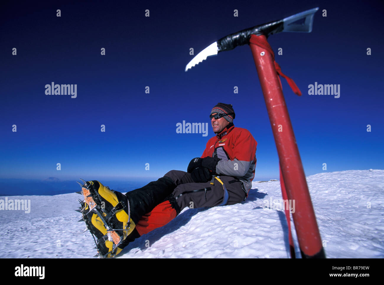 A climber and his axe take in the view from the summit of Mount Rainier ...
