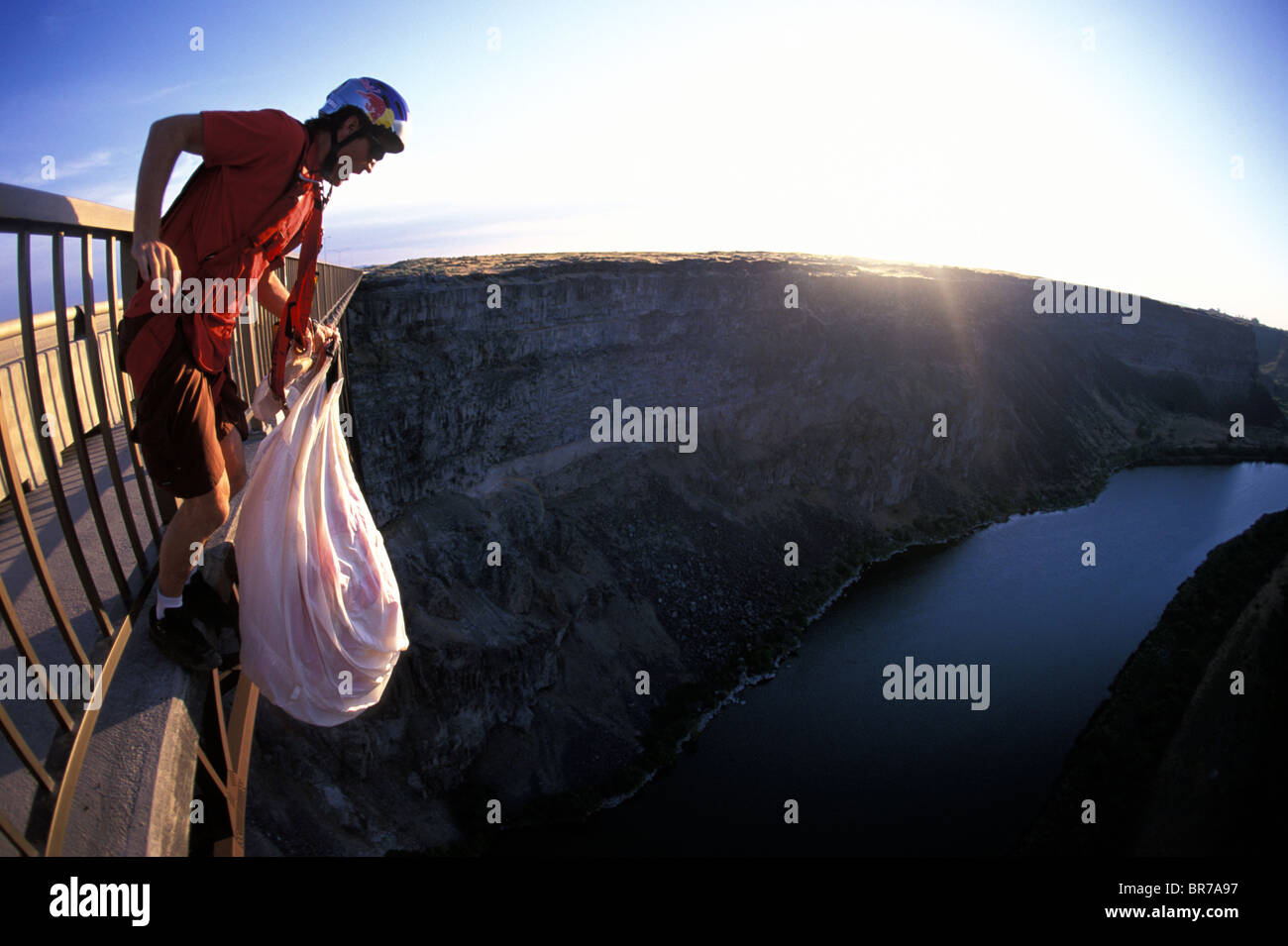 A BASE jumper holds his parachute as he gets ready to jump off of a ...