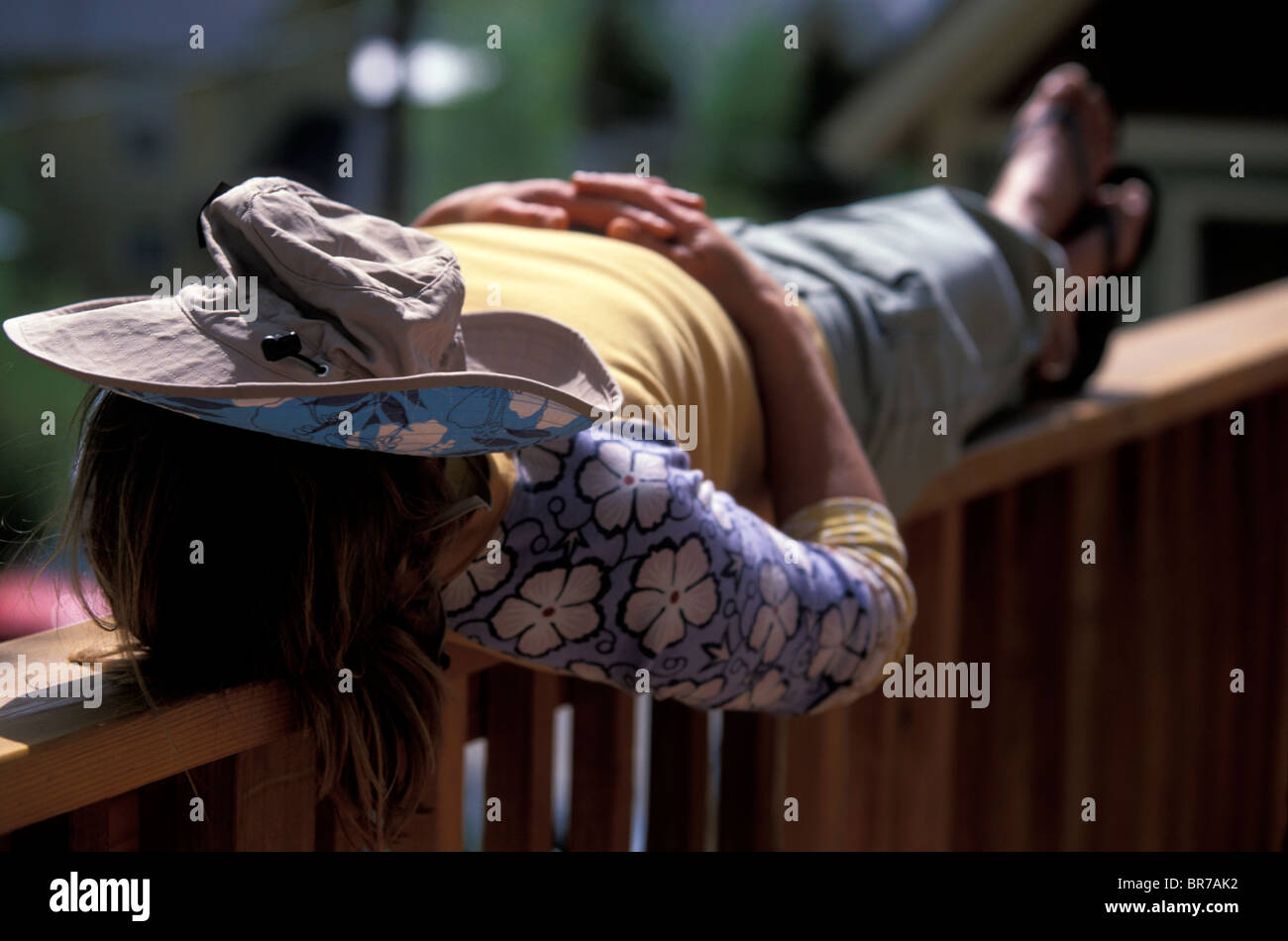 A woman napping on a railing with a hat over her face in Telluride ...