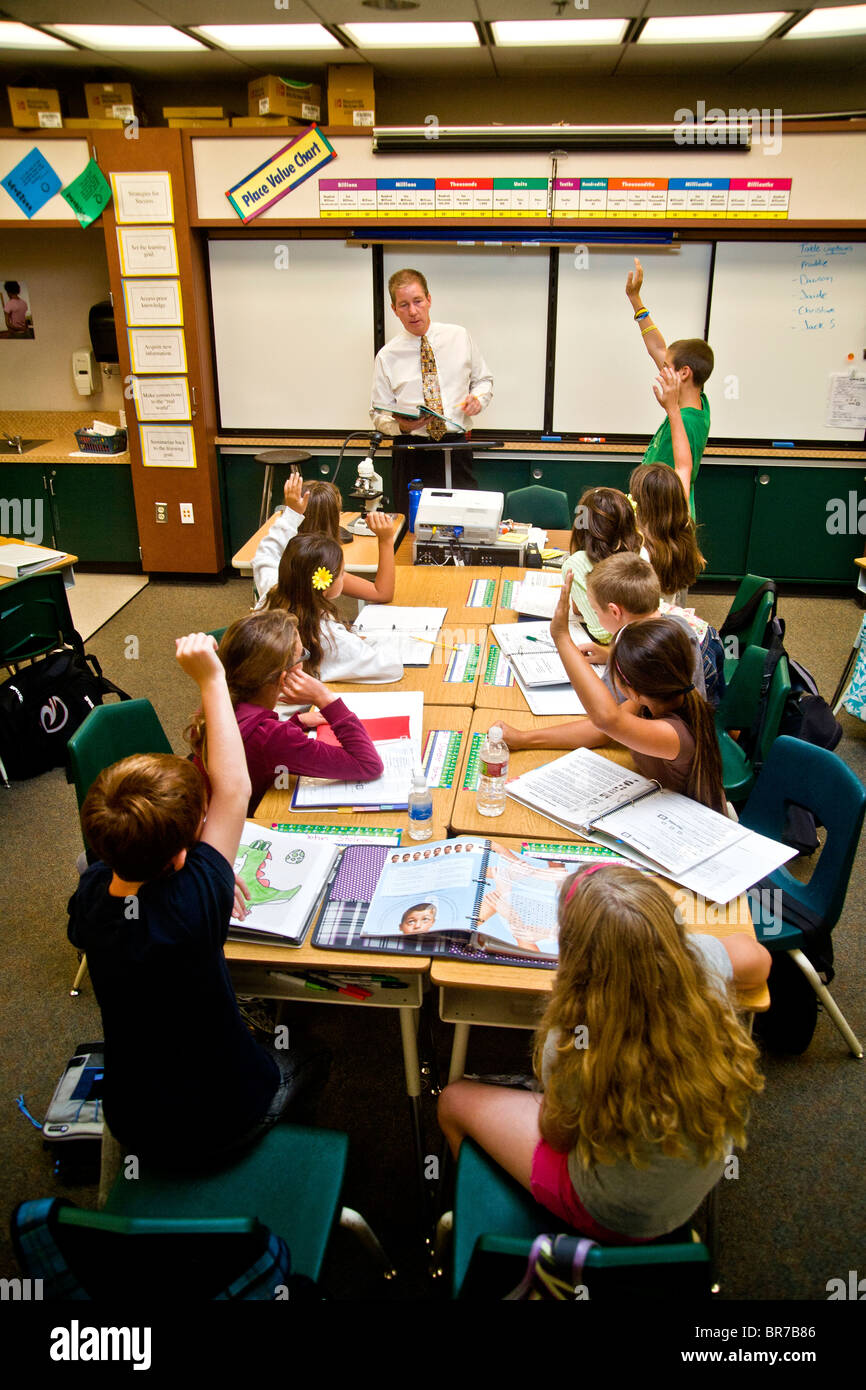 Students' hands go up in answer to a question as a middle school ...