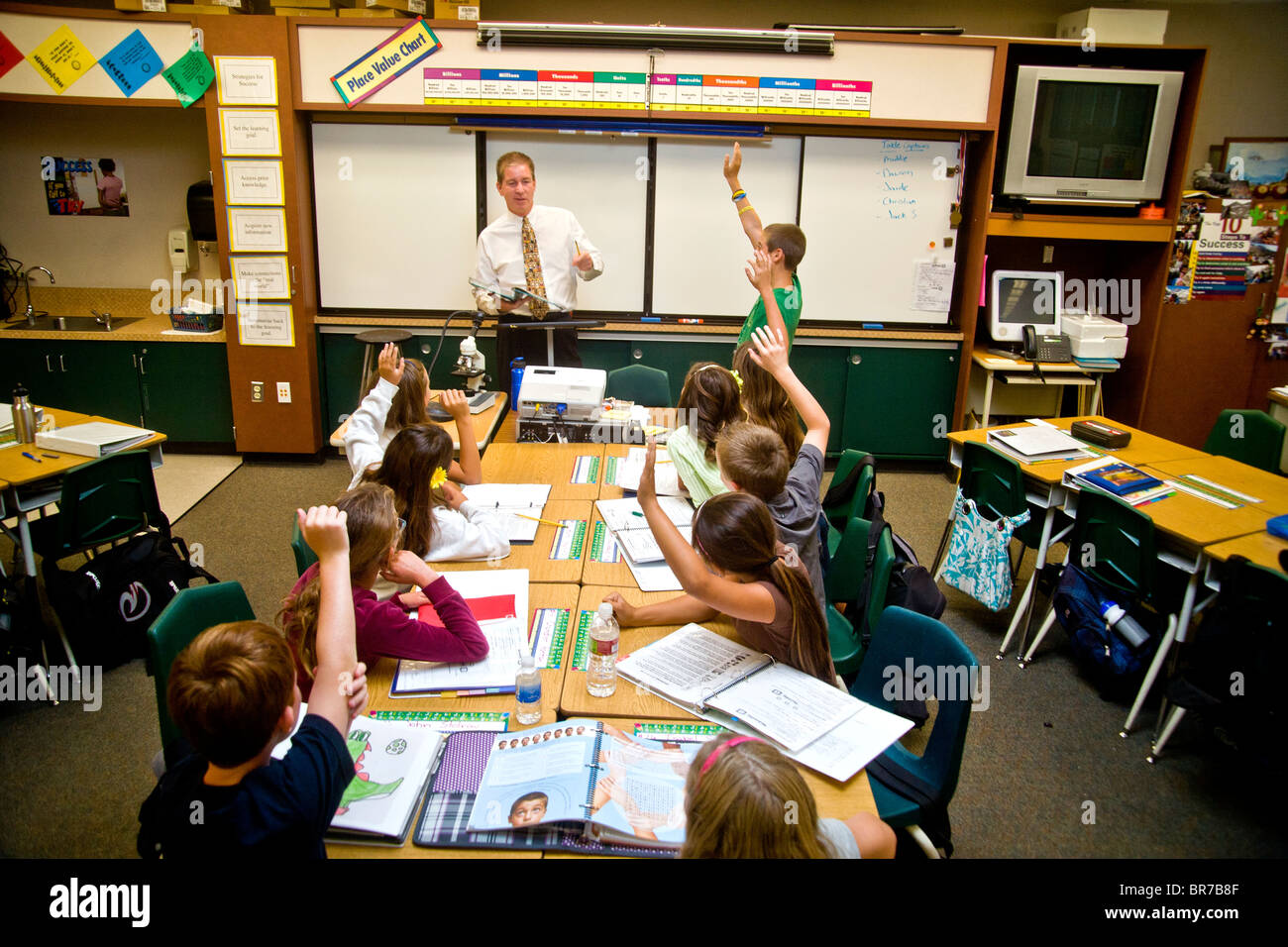 Students' hands go up in answer to a question as a middle school ...