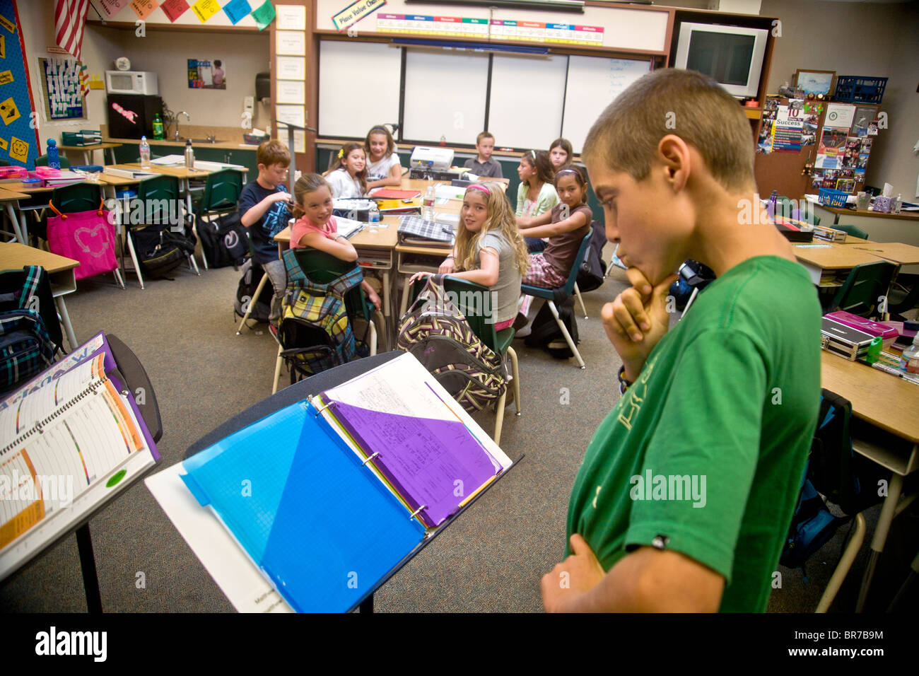 A middle school student seems unsure of himself as he checks his notes ...