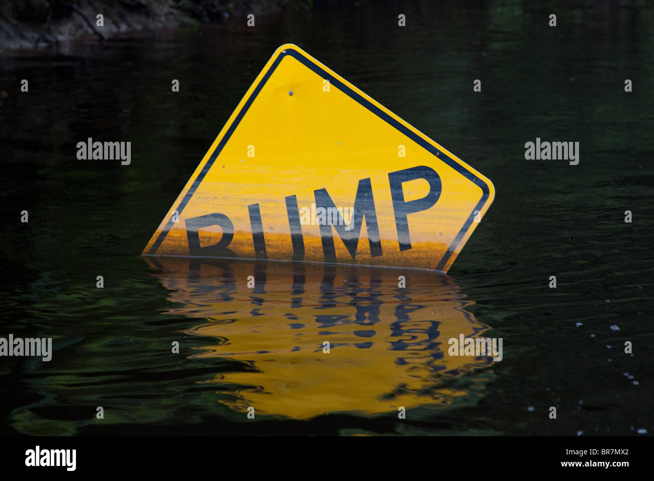 Road sign half sunken in dark water, bump in road Stock Photo - Alamy