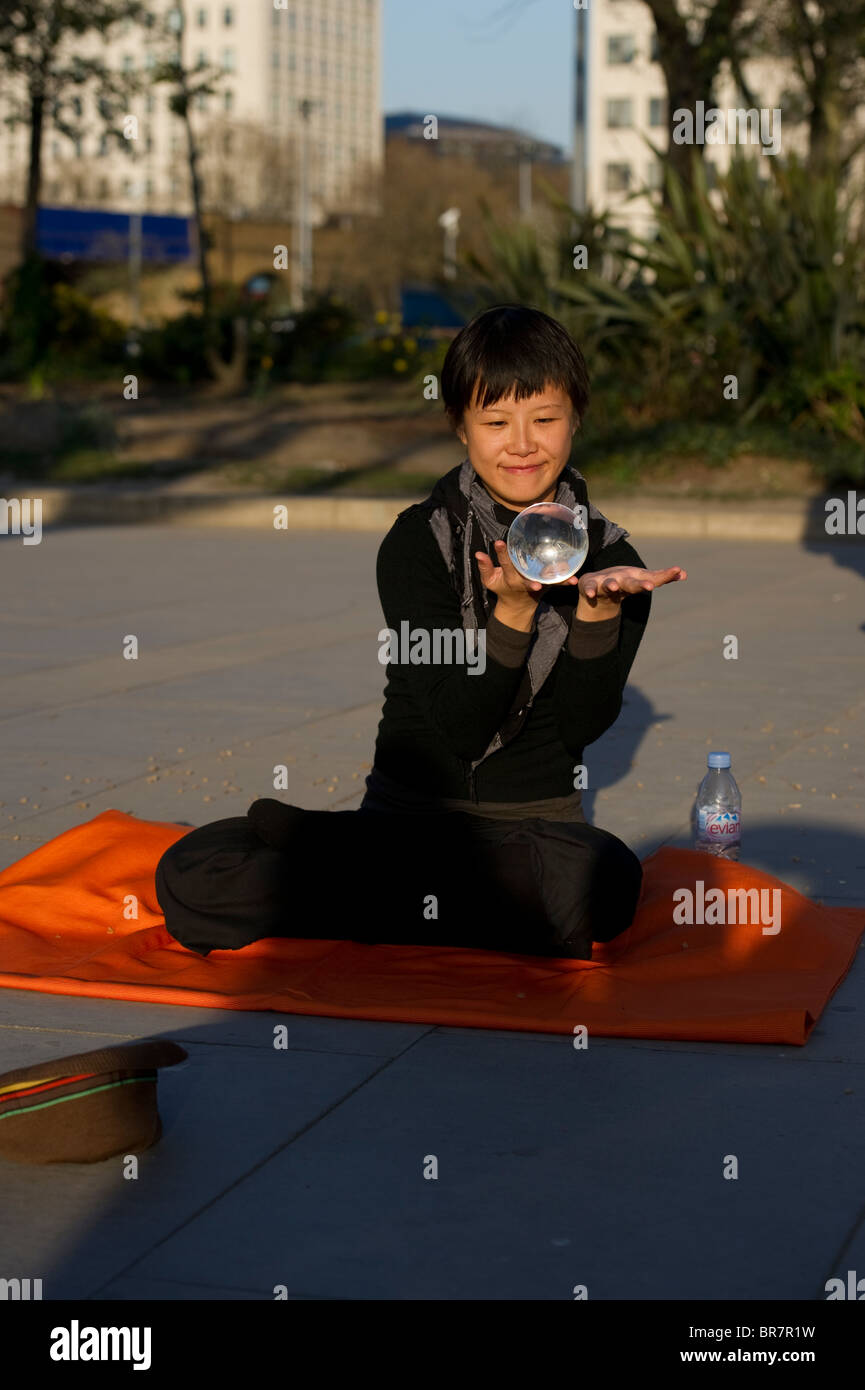 Female Chinese street performer working with glass sphere on the South ...