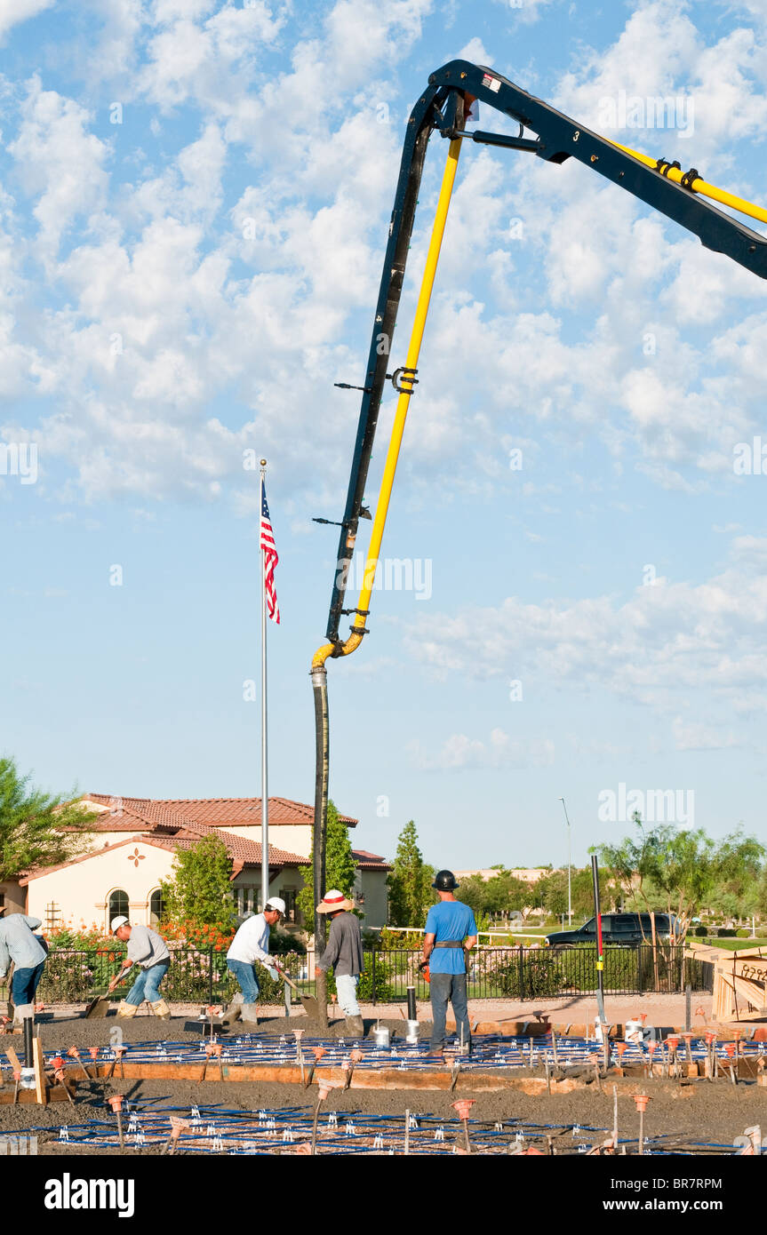 A crew of workers pour a concrete slab for a new house under ...