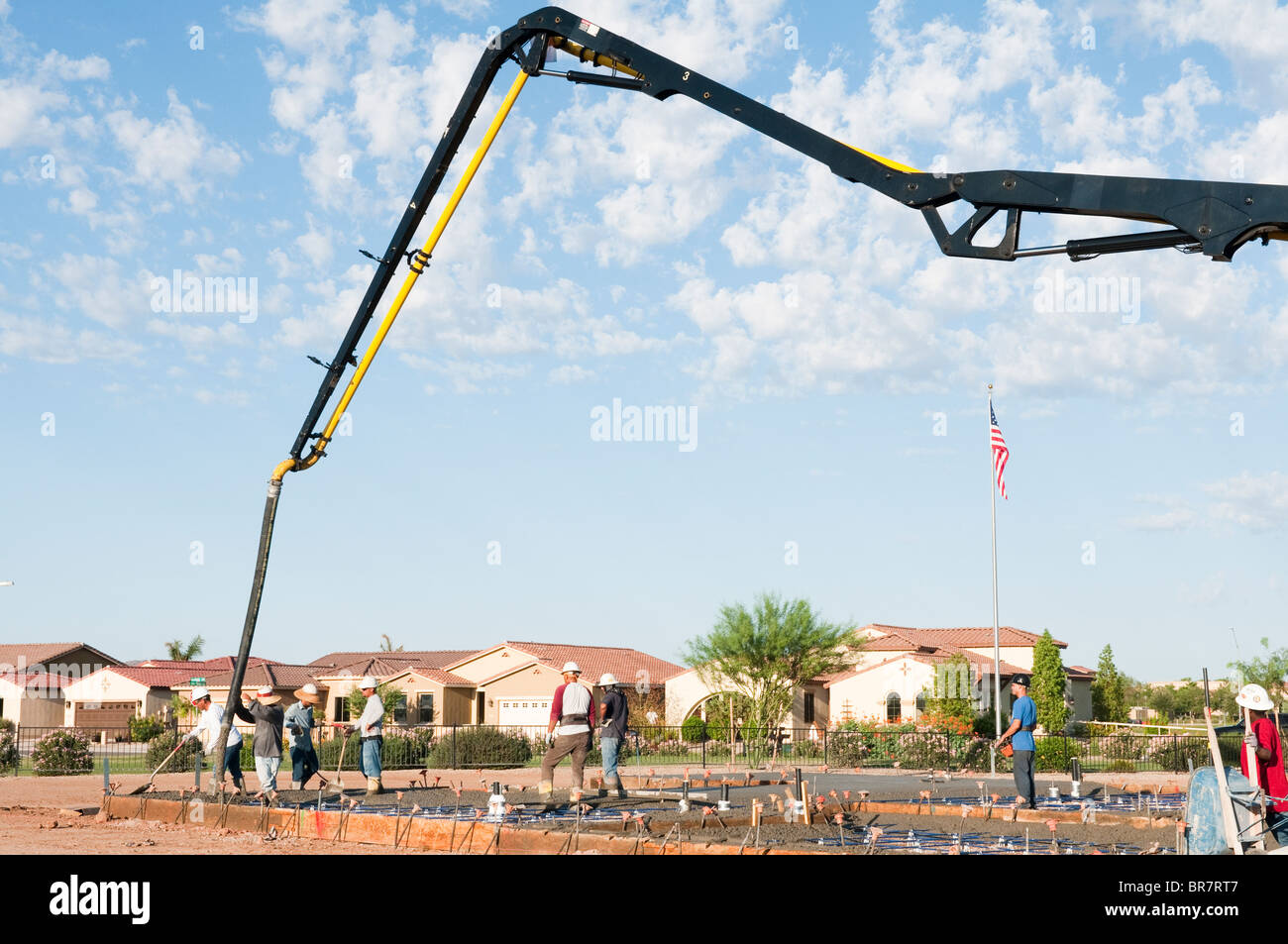 A crew of workers pour a concrete slab for a new house under ...