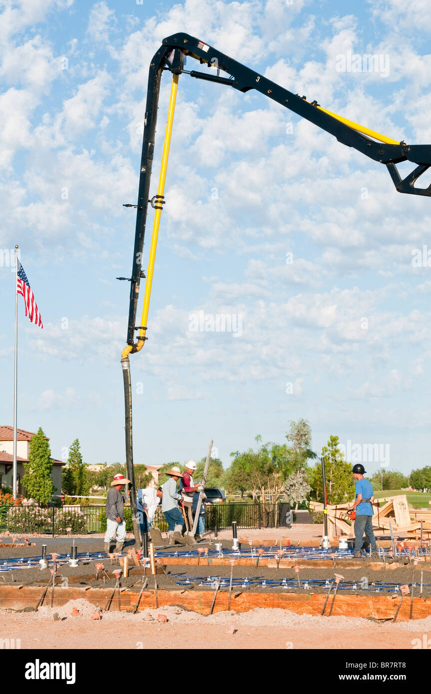 A crew of workers pour a concrete slab for a new house under ...
