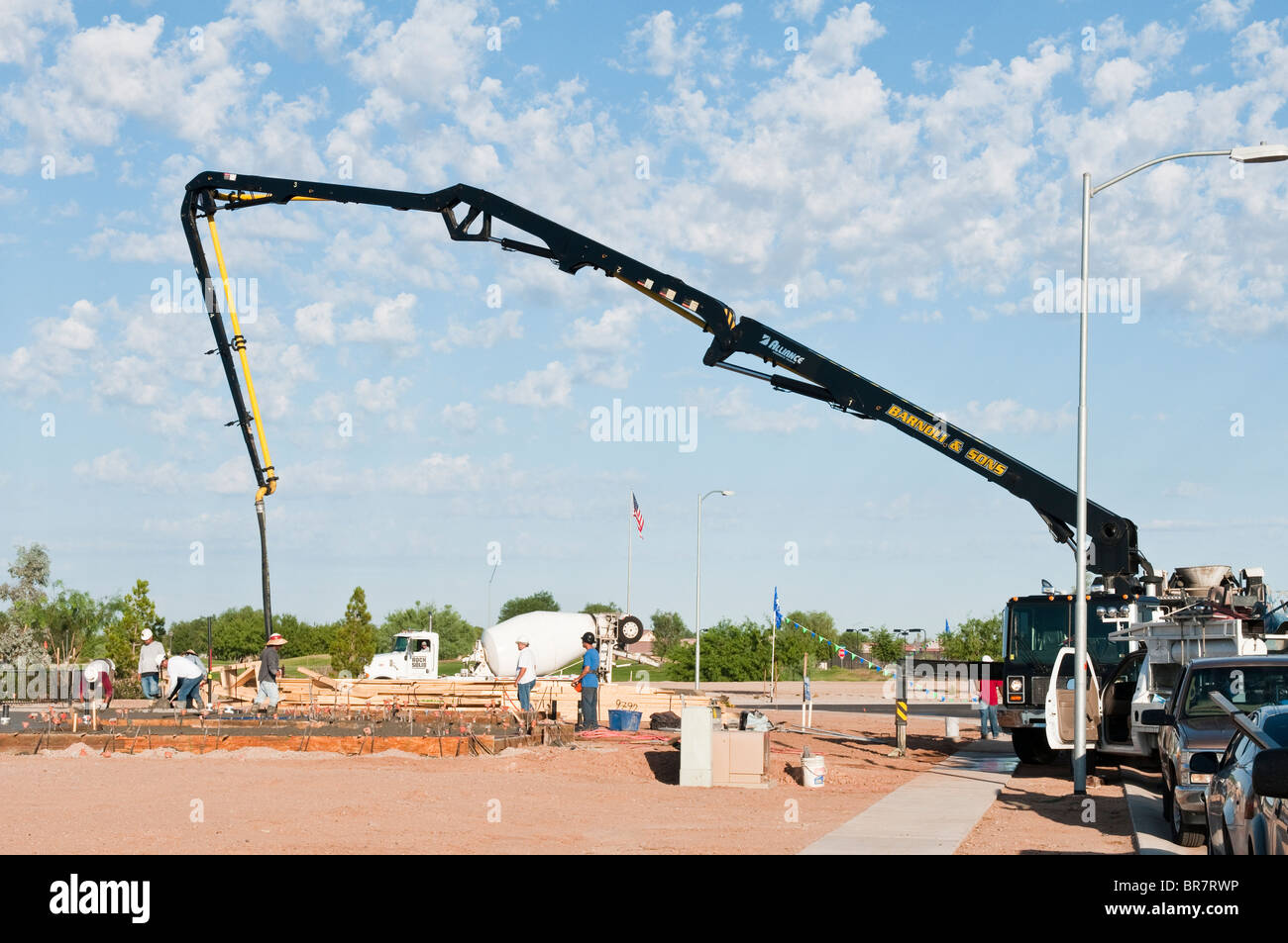 A crew of workers pour a concrete slab for a new house under ...