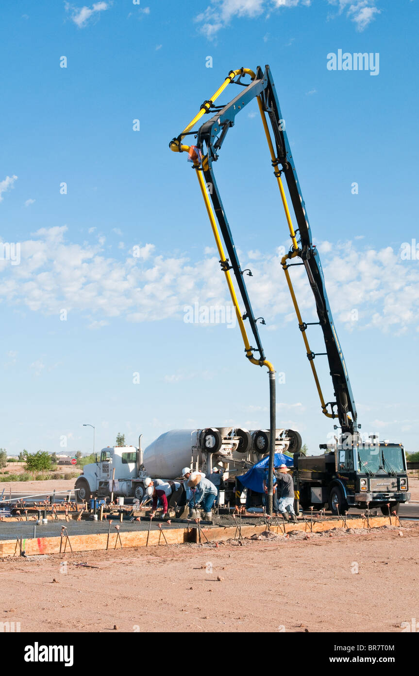 A crew of workers pour a concrete slab for a new house under ...