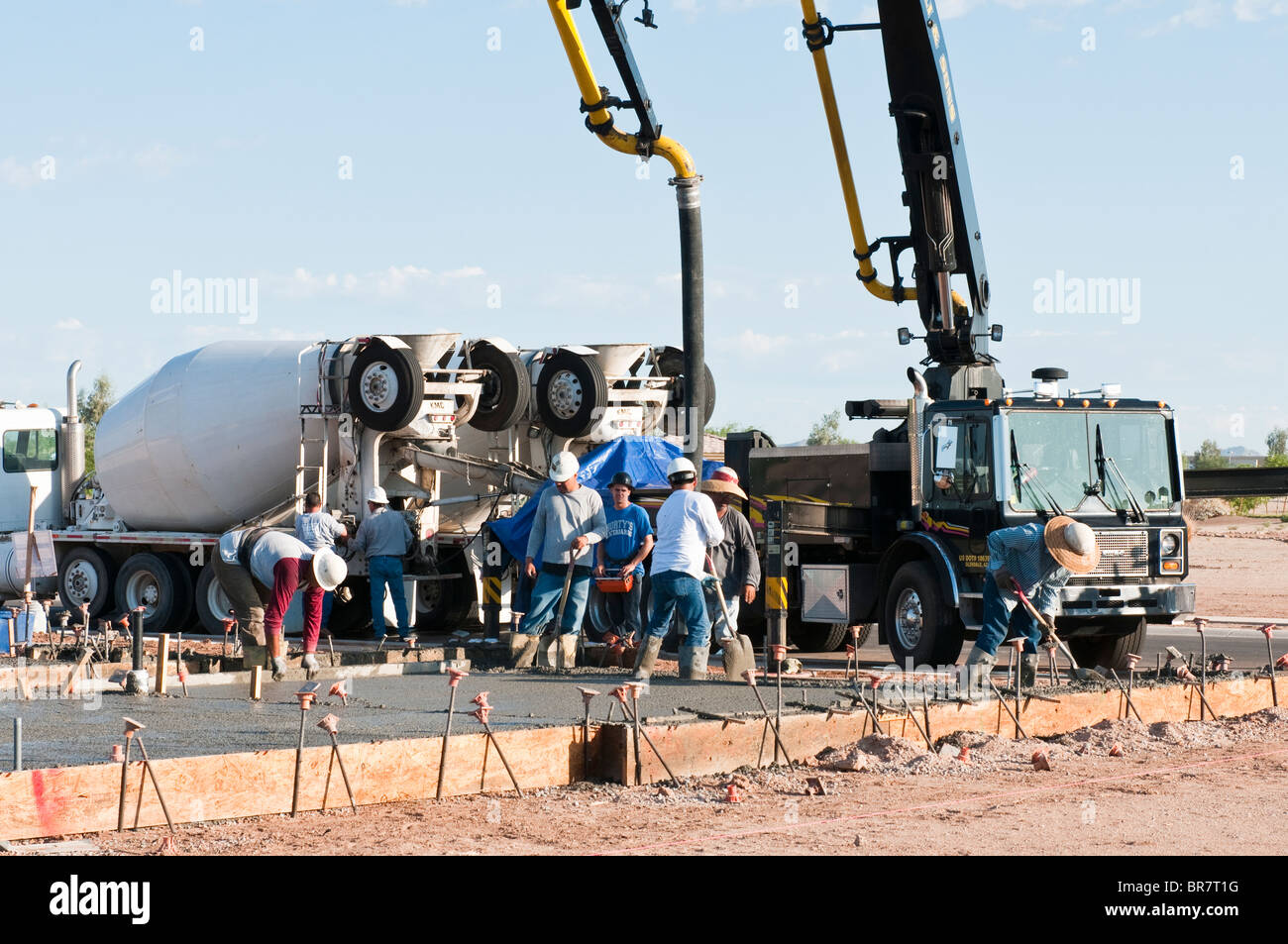 A crew of workers pour a concrete slab for a new house under ...
