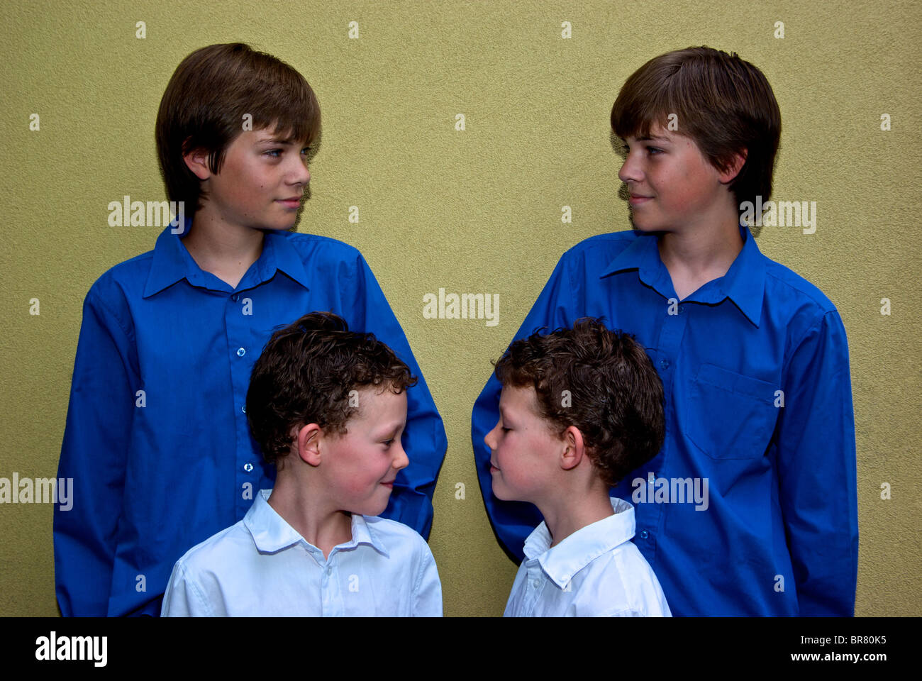 Two set of identical preteen male twins dressed alike in same clothing ...