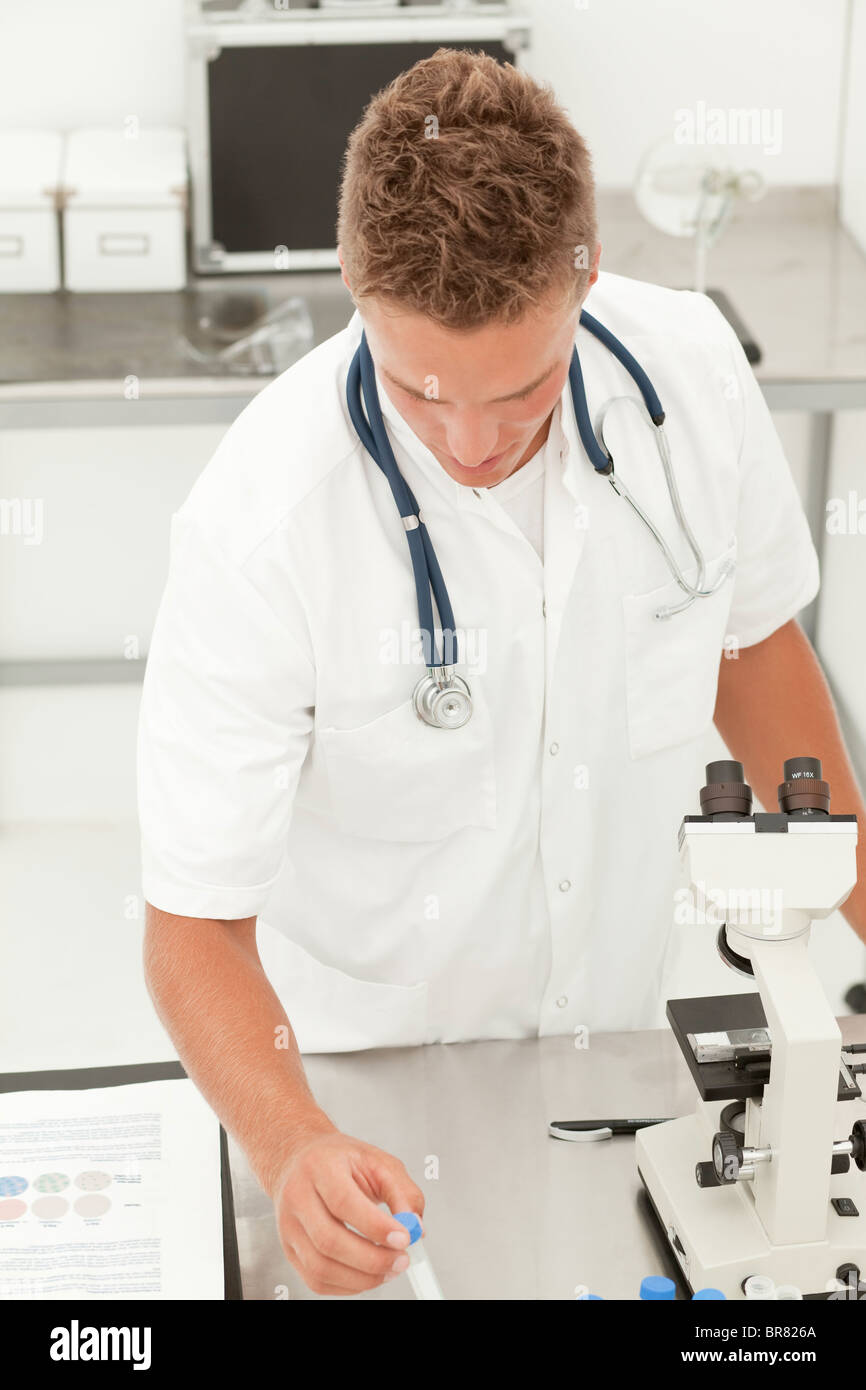 Young blond handsome doctor standing in lab, checking results of ...
