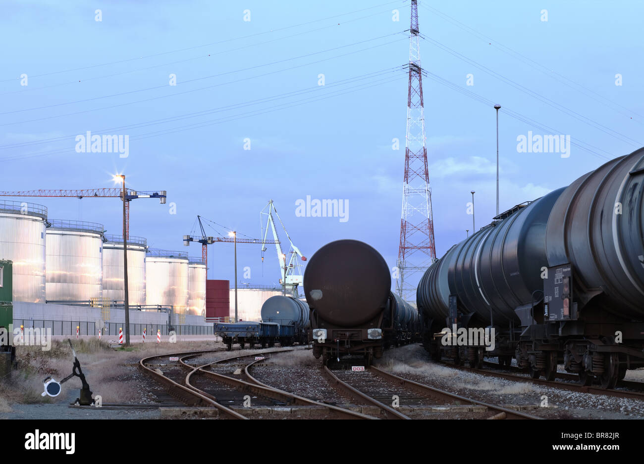 Oil tank cars standing on rail tracks in industrial area; twilight ...
