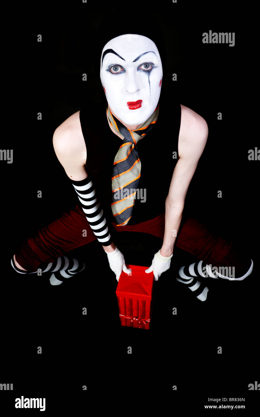 portrait of mime with red gift box on black background Stock Photo - Alamy