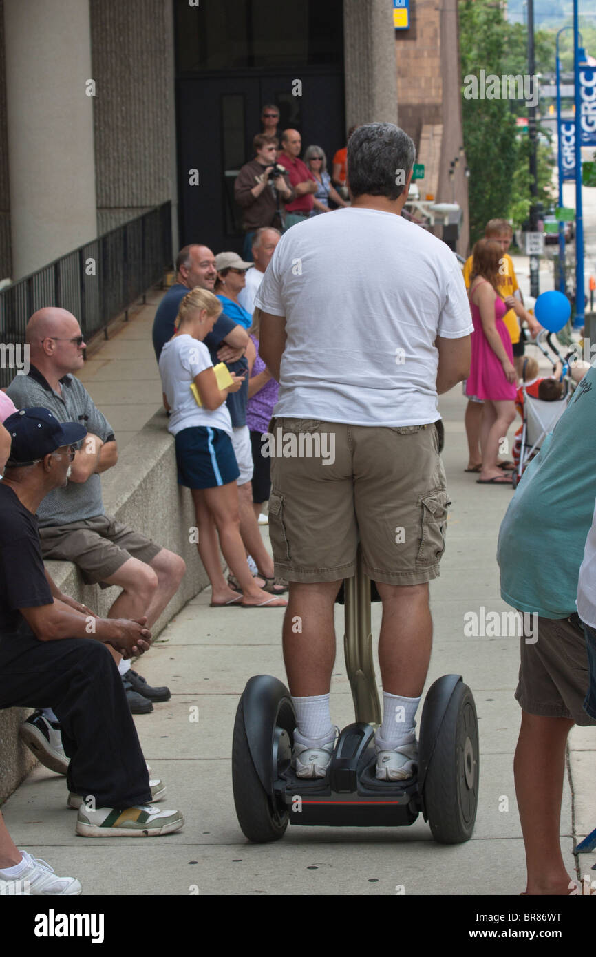 A young man riding Segway scooter on city street inspired rear view ...