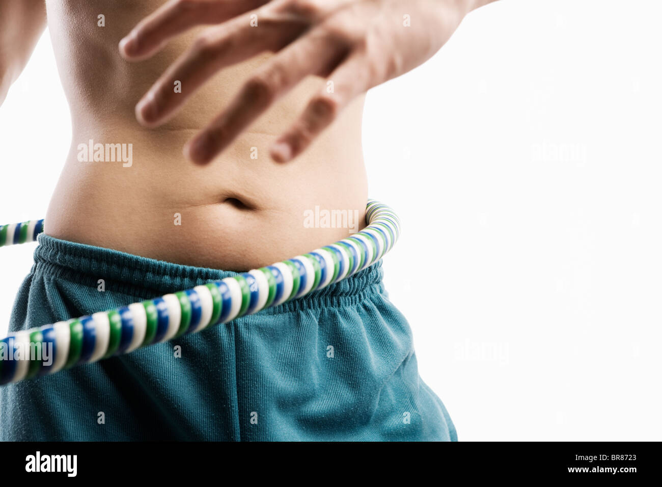 Man, showing only body part playing hula hoop against white background ...