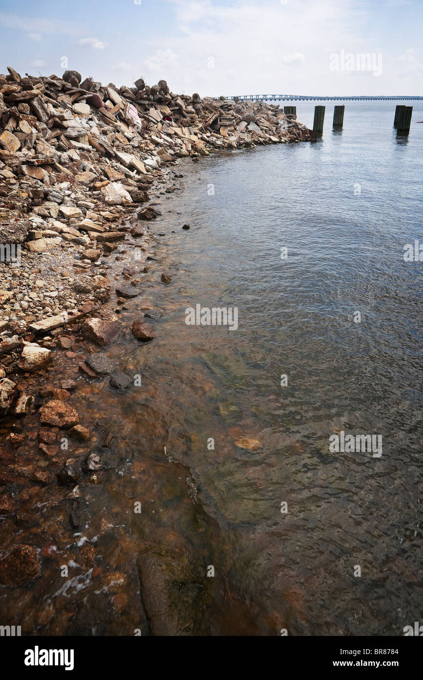 Red oil boom in the water in a quiet bay with wooden pilings and a ...