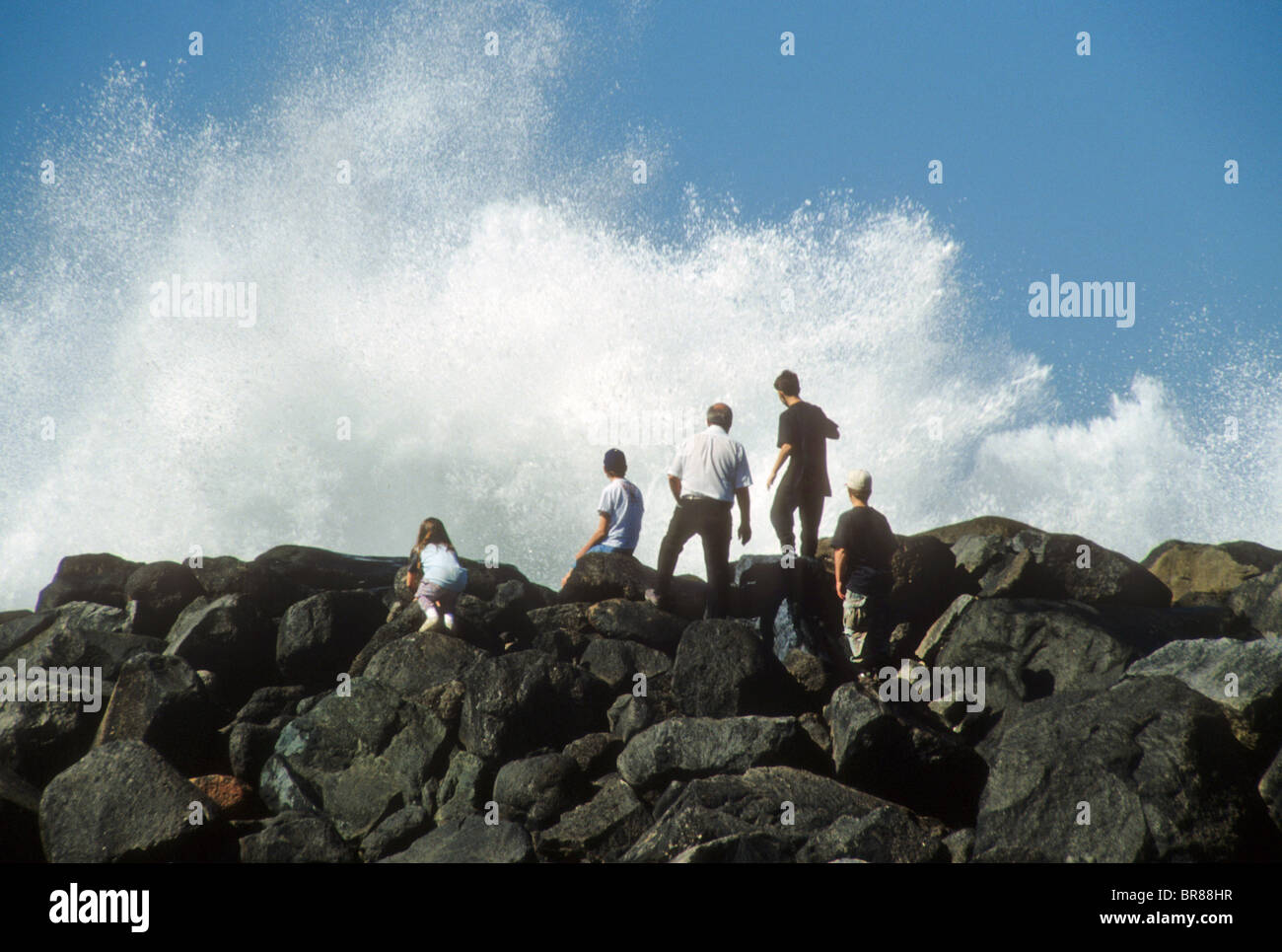 People climb rocks beach crashing wave surf ocean sea danger threat ...