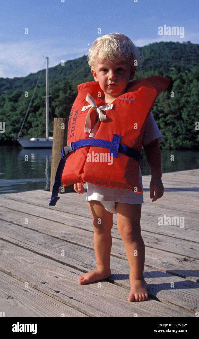 A little boy standing on a jetty wearing a life jacket Stock Photo - Alamy