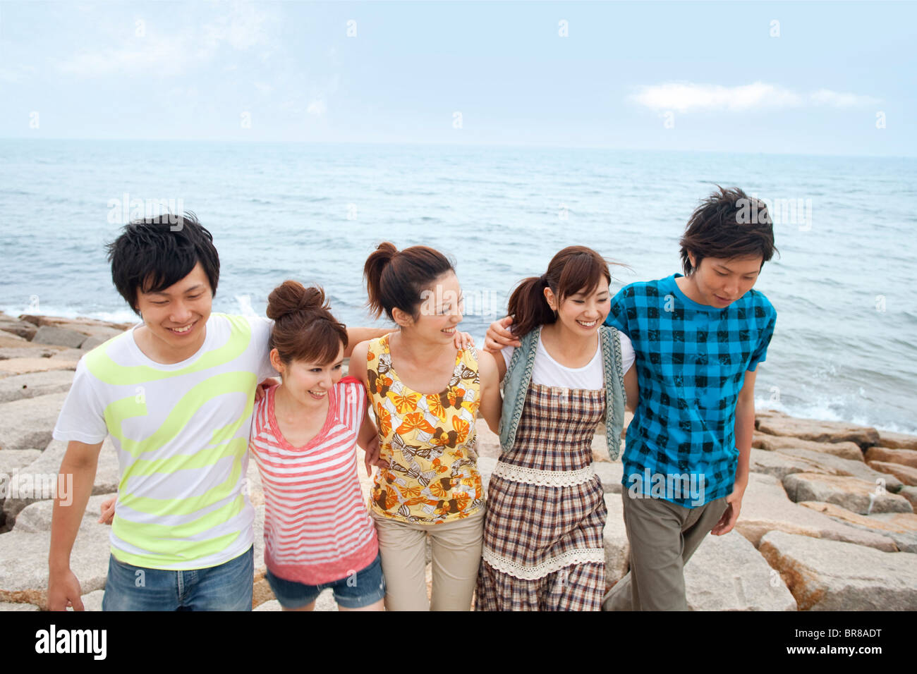 Five young people walking side by side at beach Stock Photo - Alamy