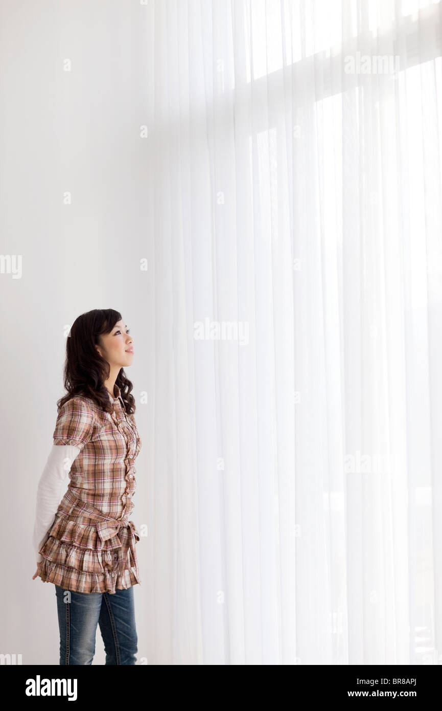 Young woman standing by window, copy space Stock Photo - Alamy