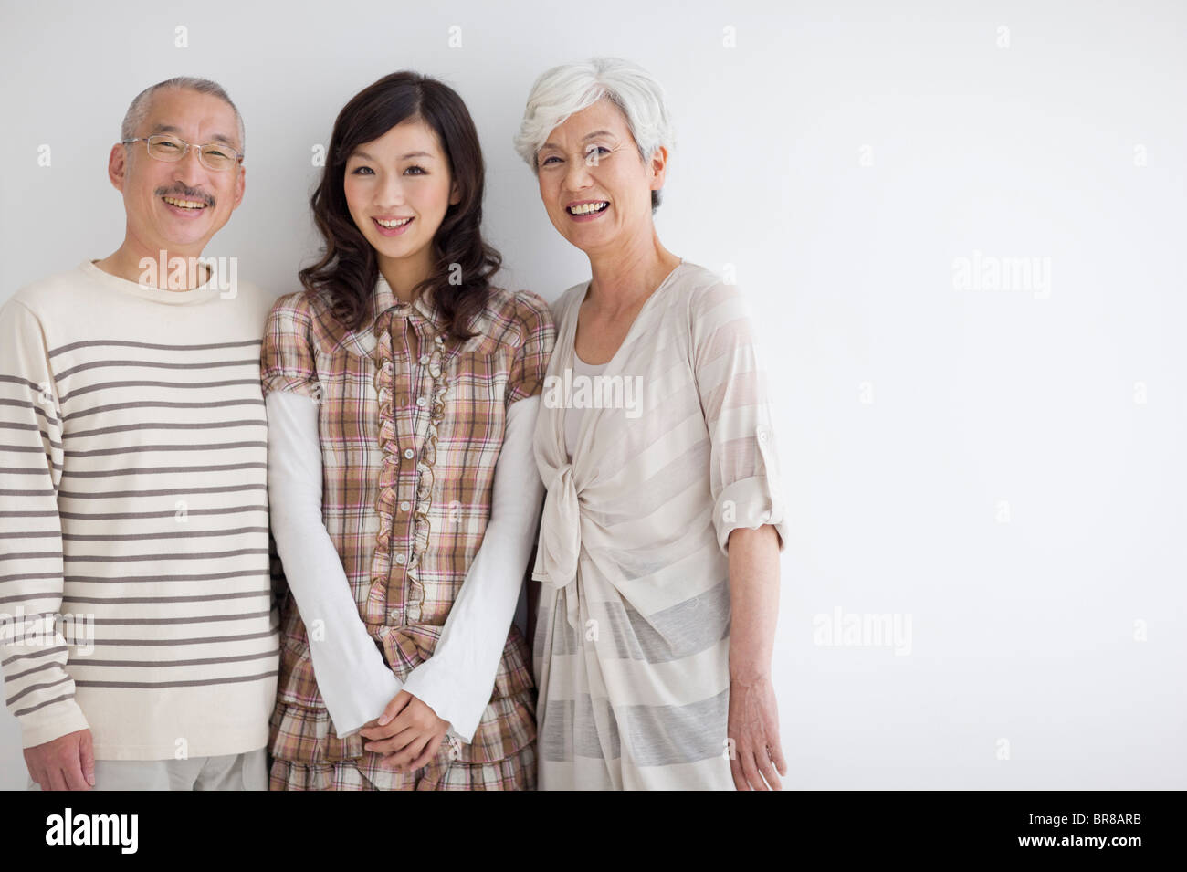 Portrait of family standing side by side, smiling, white background ...
