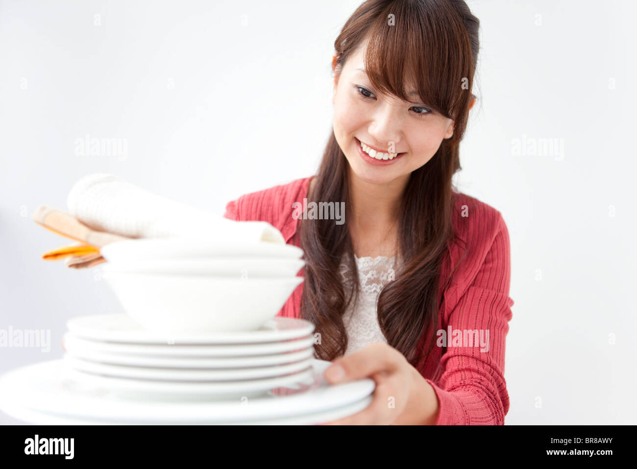 Young woman holding pile of plates, white background Stock Photo - Alamy