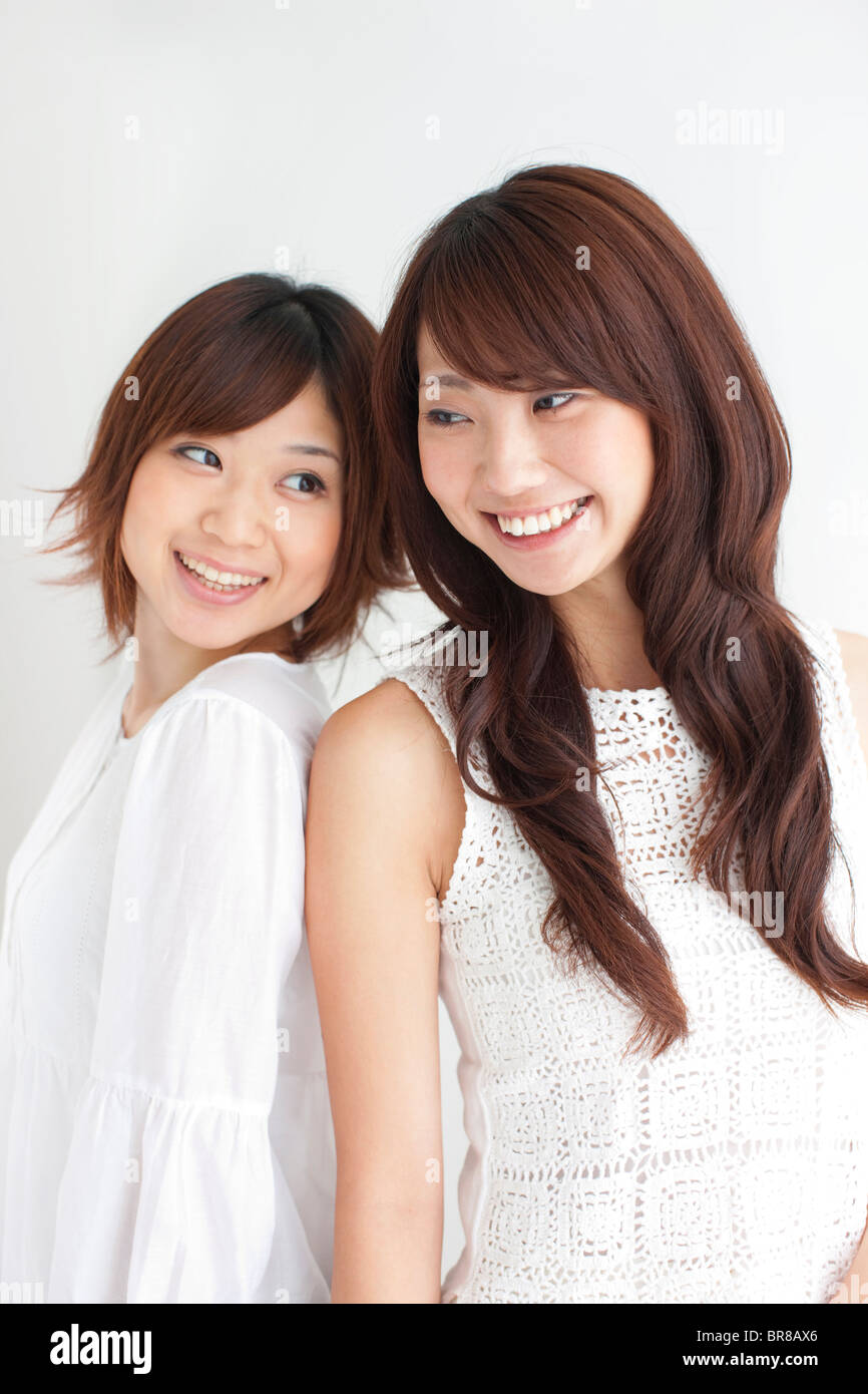 Two young women standing back to back, white background Stock Photo - Alamy