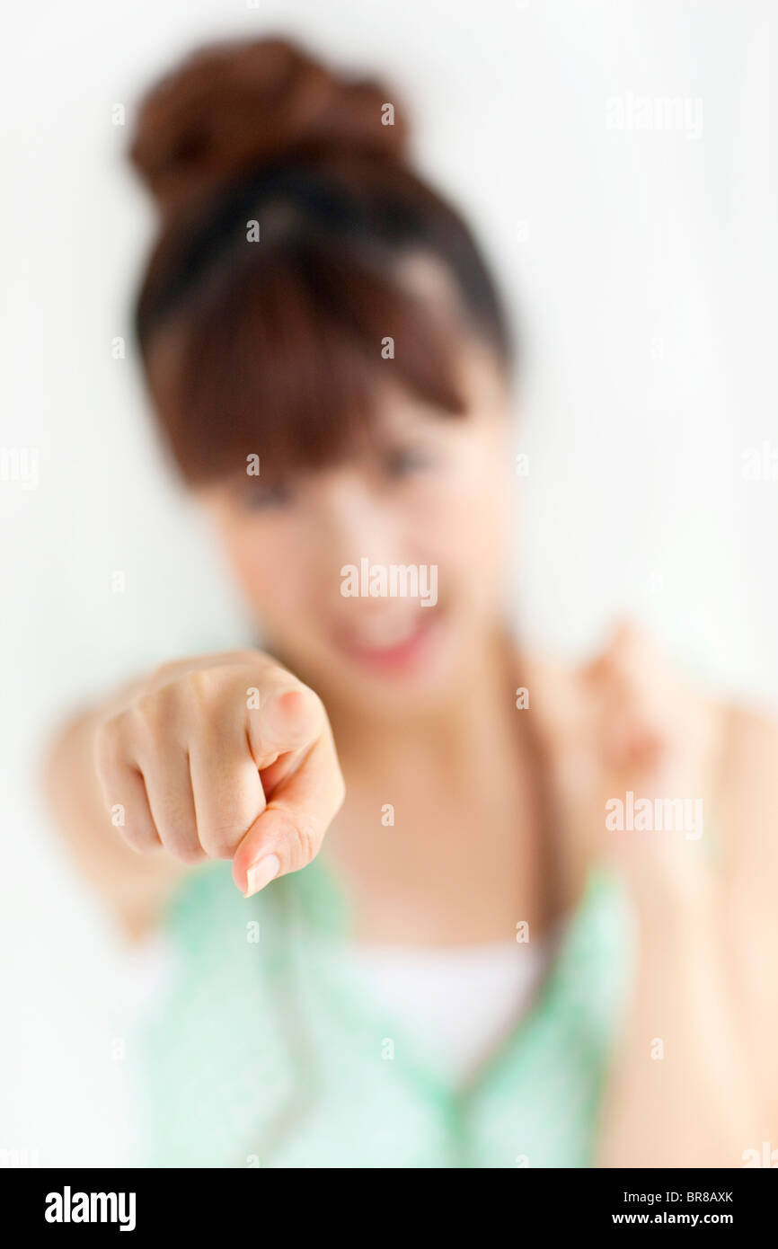 Young woman pointing forward, white background, differential focus ...
